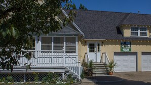 Uma casa de dois andares com varanda da frente, garagem e uma placa com a inscrição 'House'.