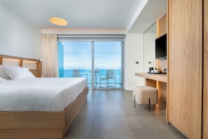 Quarto de hotel moderno com uma cama grande, uma mesa, uma TV e uma varanda com vista.