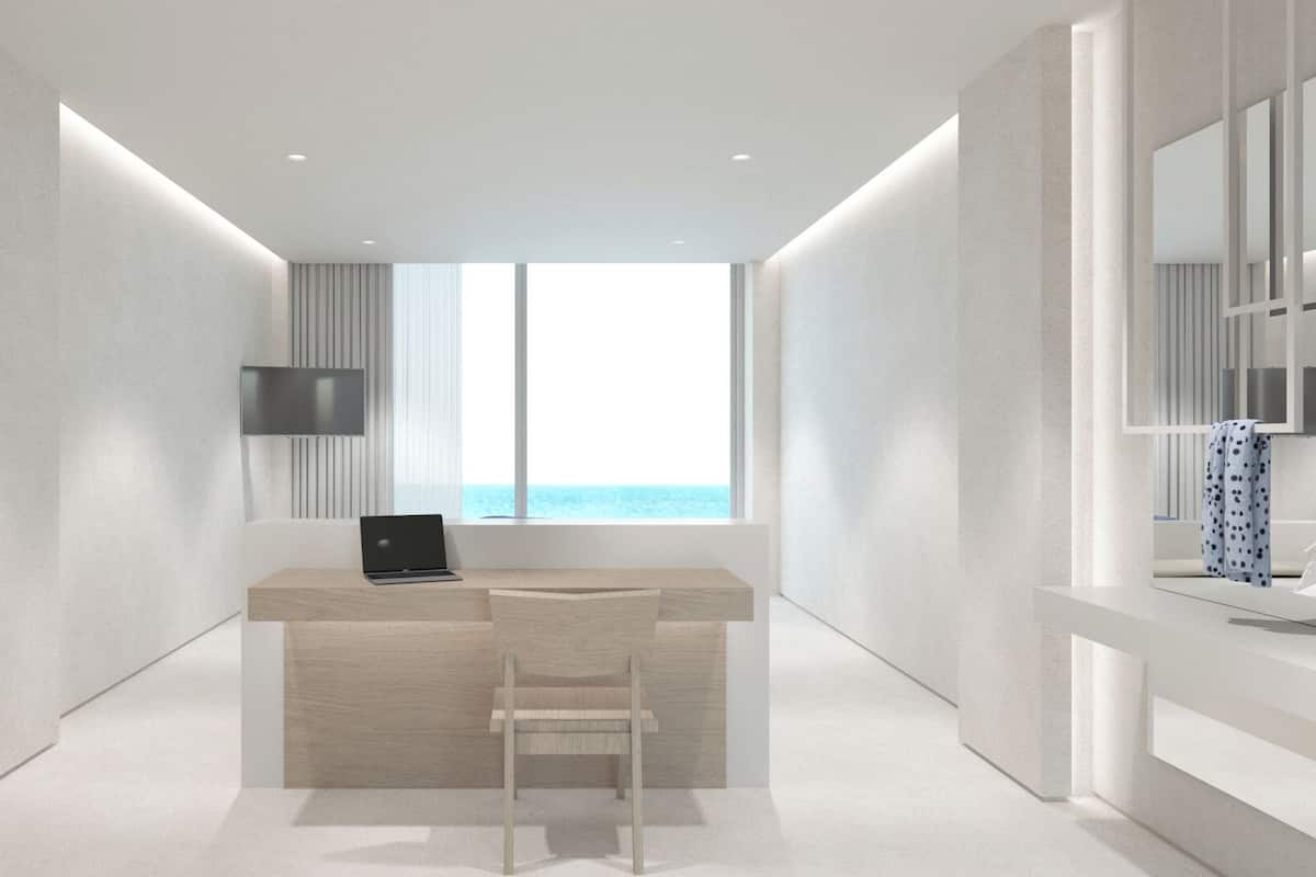 Quarto moderno e minimalista com escrivaninha, cadeira e uma janela grande com vista para o mar.
