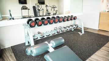 Uma academia com um banco, halteres e equipamentos de exercício.