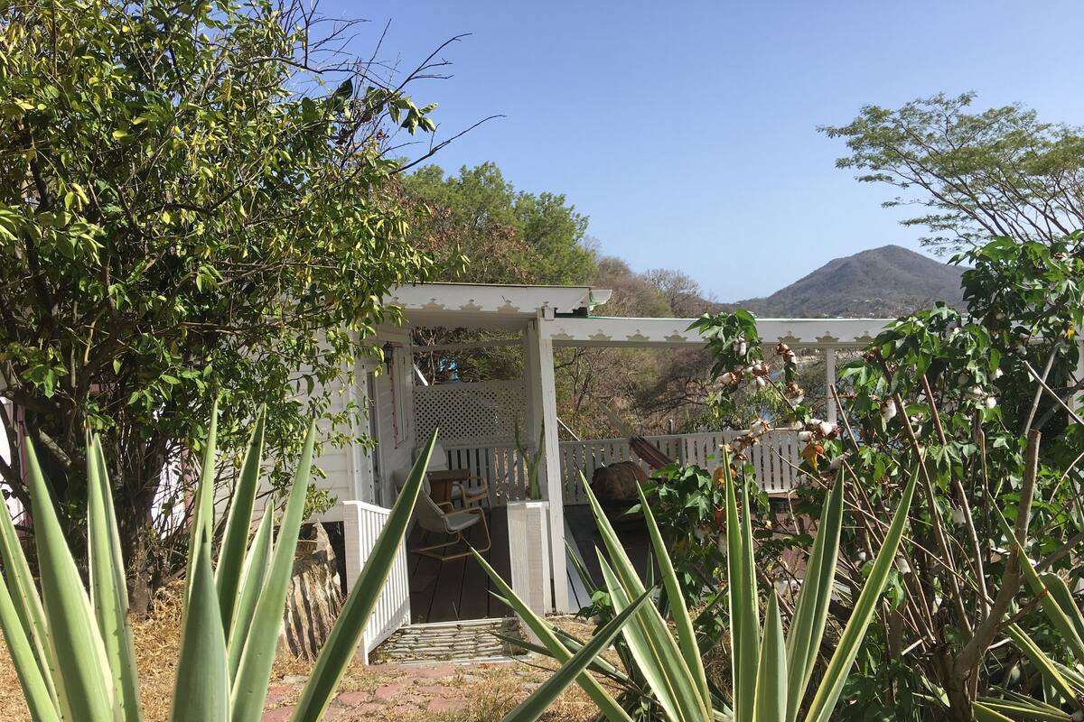 Um jardim com pérgola, área de estar e vista para uma montanha.
