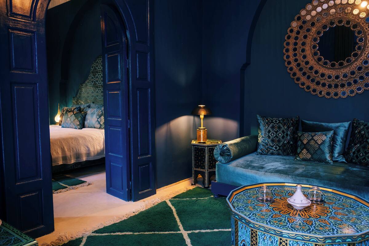 Um quarto com uma cama, um sofá, uma mesa de centro estampada e um espelho decorativo.