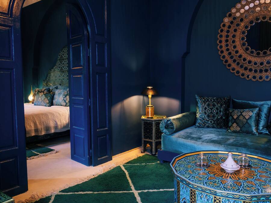 Um quarto com uma cama, um sofá, uma mesa de centro estampada e um espelho decorativo.