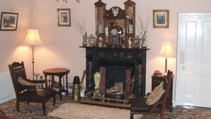 Uma sala de estar tradicional com lareira, um candelabro e móveis clássicos.
