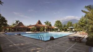 Piscina com deck revestido, um gazebo e uma montanha ao fundo.