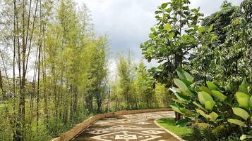 Um caminho com um padrão geométrico de azulejos, cercado por bambu e outras plantas.