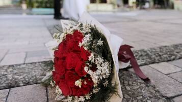 Cena de casamento com um buquê no chão e um edifício ao fundo.