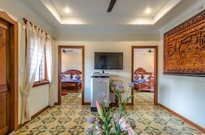Quarto de hotel com uma cama grande, televisão, frigorífico e um objeto decorativo na parede.
