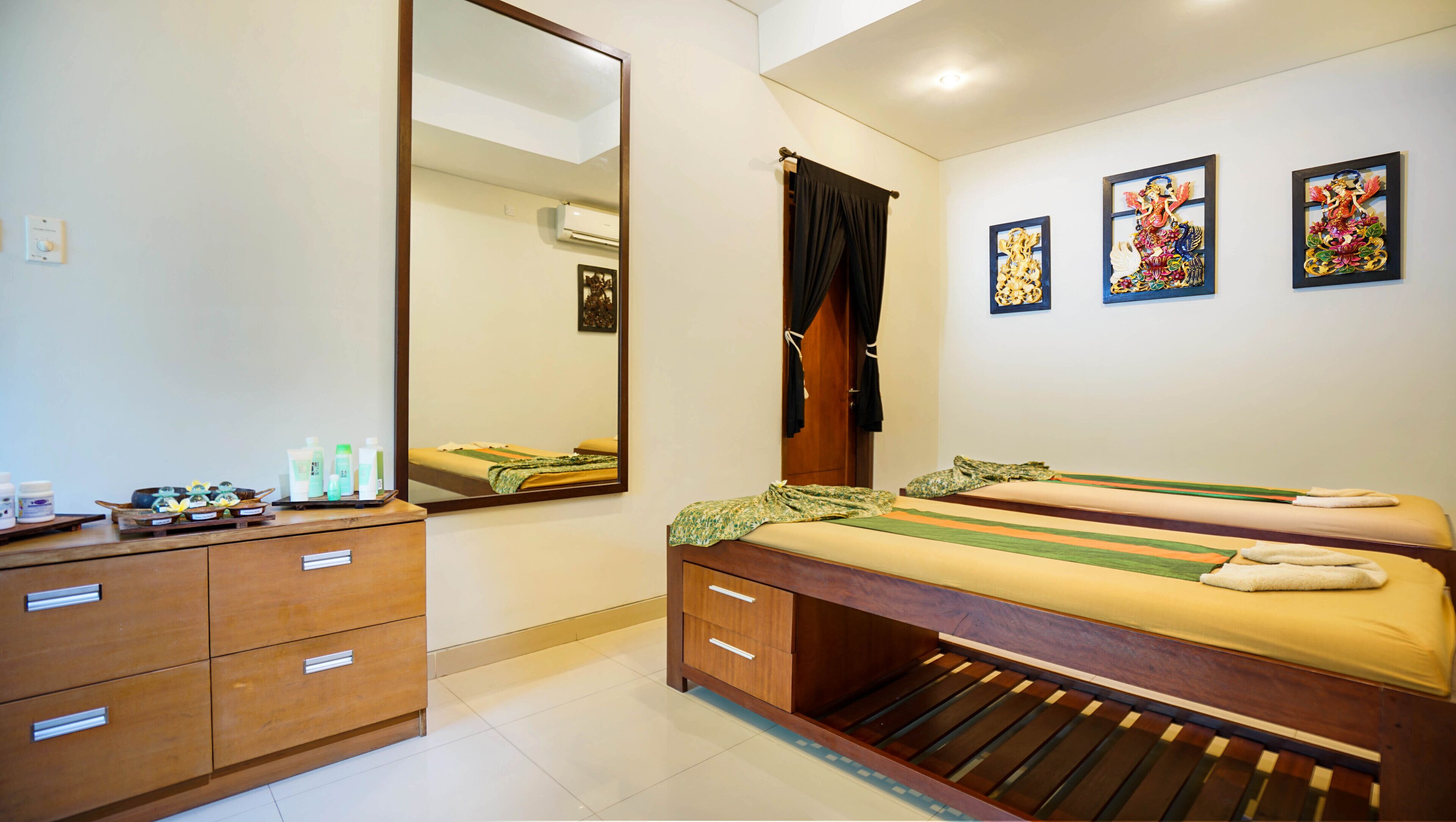 Quarto com cama de madeira, cómoda com gavetas, espelho e decoração nas paredes.