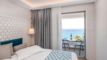 Quarto de hotel com cama, vista para o mar, varanda com mesa e cadeiras e parede com padrão.