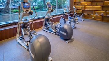 Uma academia com bicicletas ergométricas, esteira e remo.