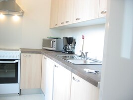 Cozinha com fogão, micro-ondas, máquina de café e pia.
