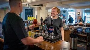 Uma área de bar com diversas torneiras de cerveja, incluindo marcas como Spitfire e Master Brew.