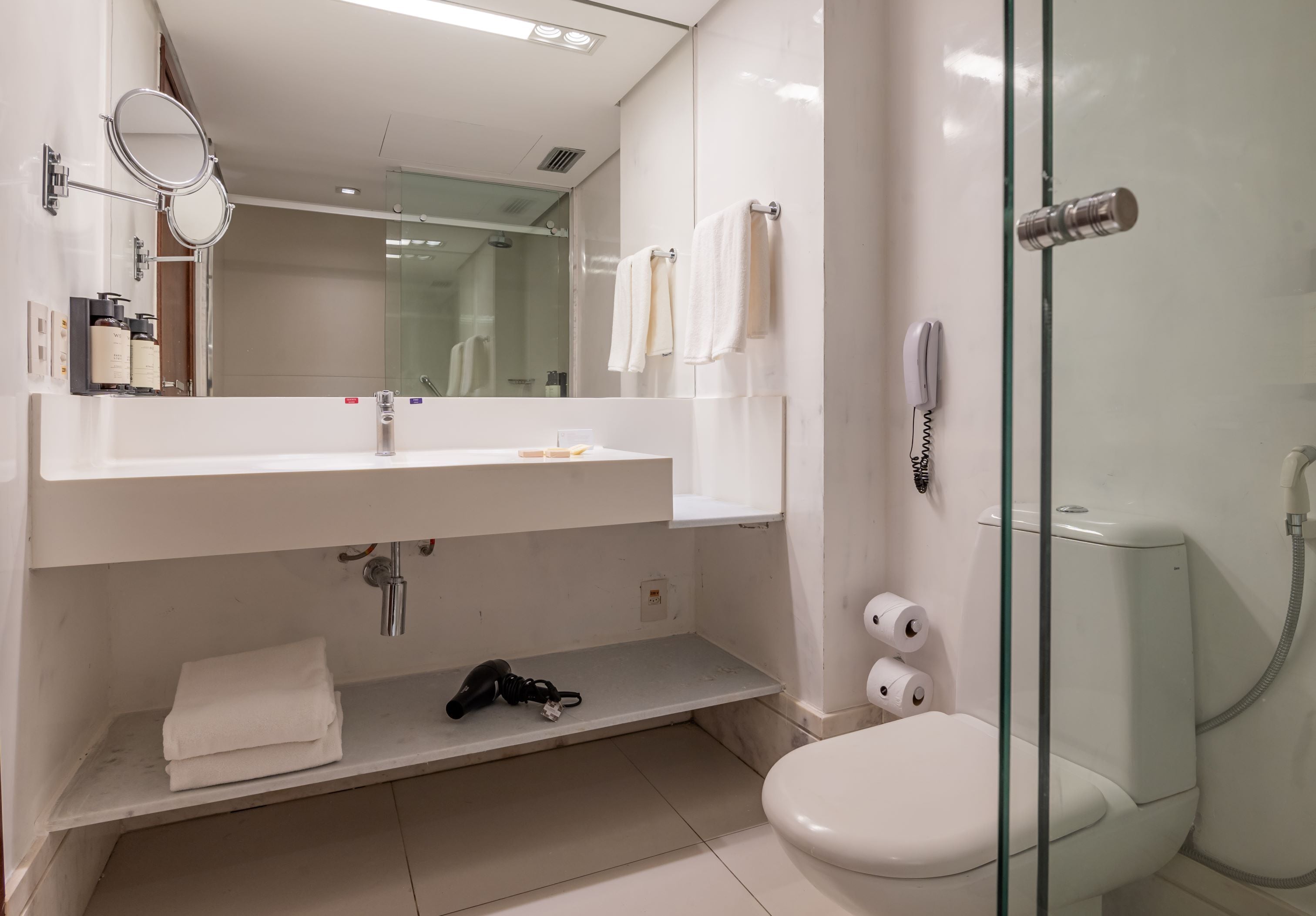 Uma casa de banho moderna com lavatório branco, espelho e sanita.