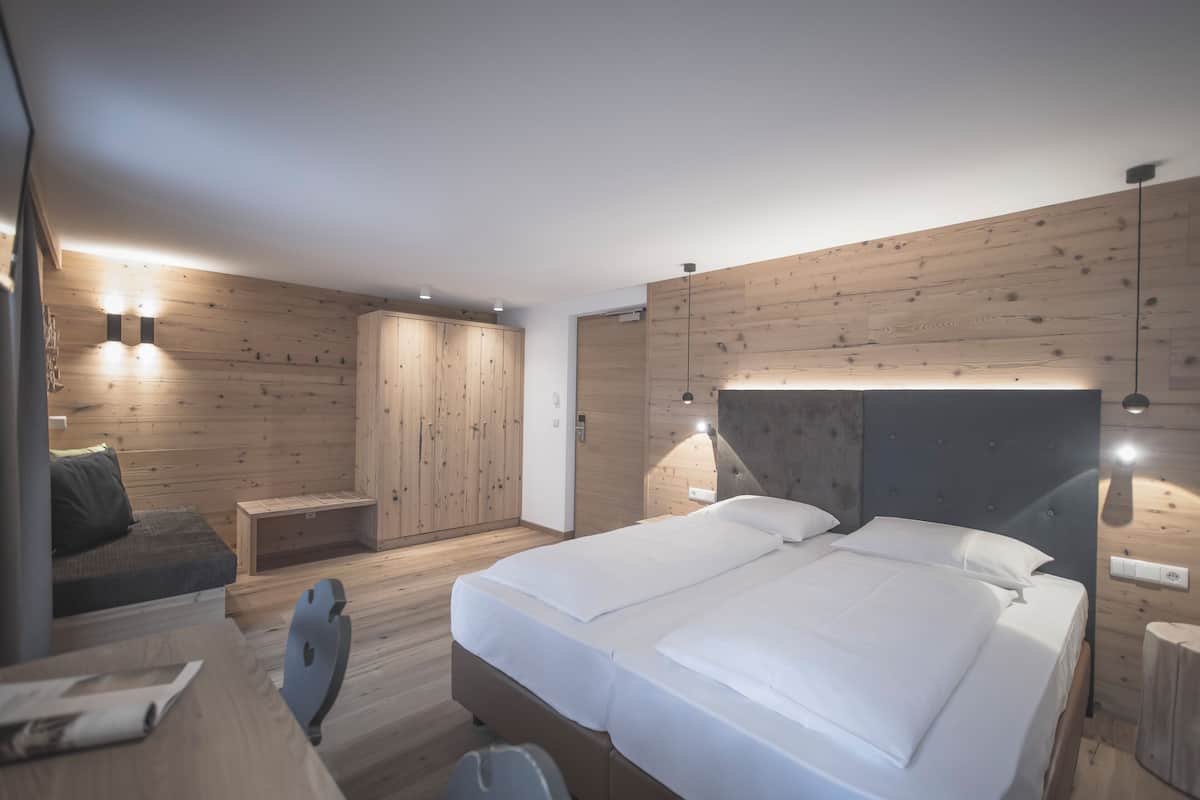 Quarto moderno com cama grande, paredes de madeira e armários embutidos.