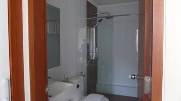 Casa de banho com sanita, lavatório e chuveiro.