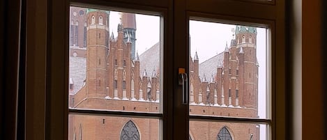 Uma janela com quatro painéis, cada um mostrando uma vista de um edifício histórico com uma torre imponente.