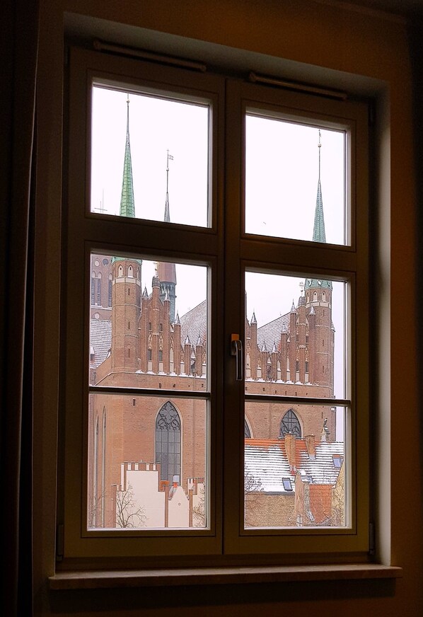 Uma janela com quatro painéis, cada um mostrando uma vista de um edifício histórico com uma torre imponente.