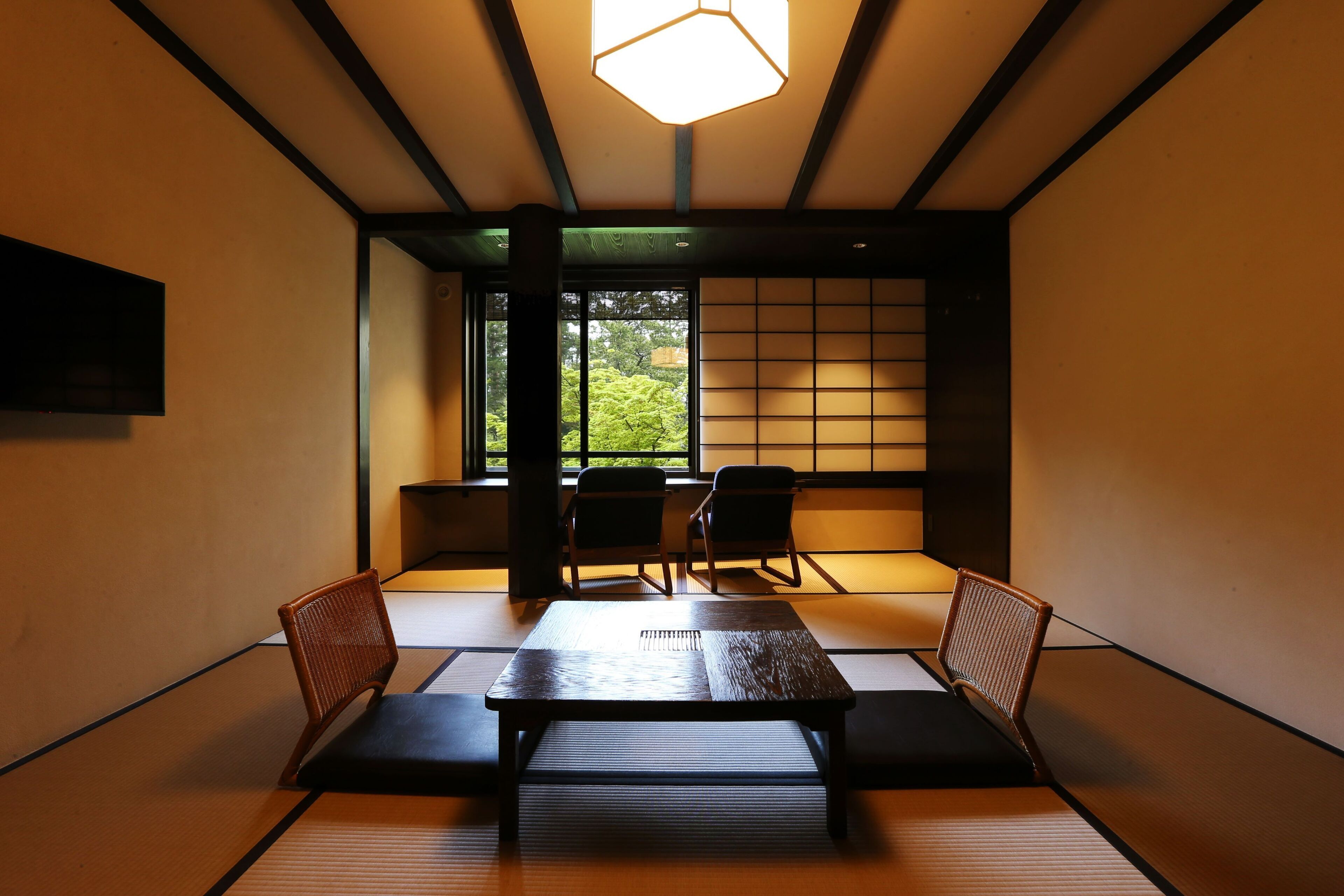Um quarto japonês tradicional com tatames, uma mesa baixa e duas cadeiras.