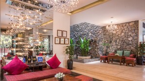Um hall amplo com parede de pedra, um candelabro e áreas de estar.