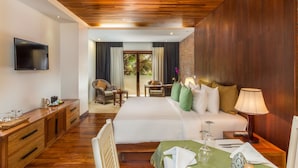 Quarto de hotel com teto de madeira, uma cama grande, televisão, área de refeições e vista para o exterior.