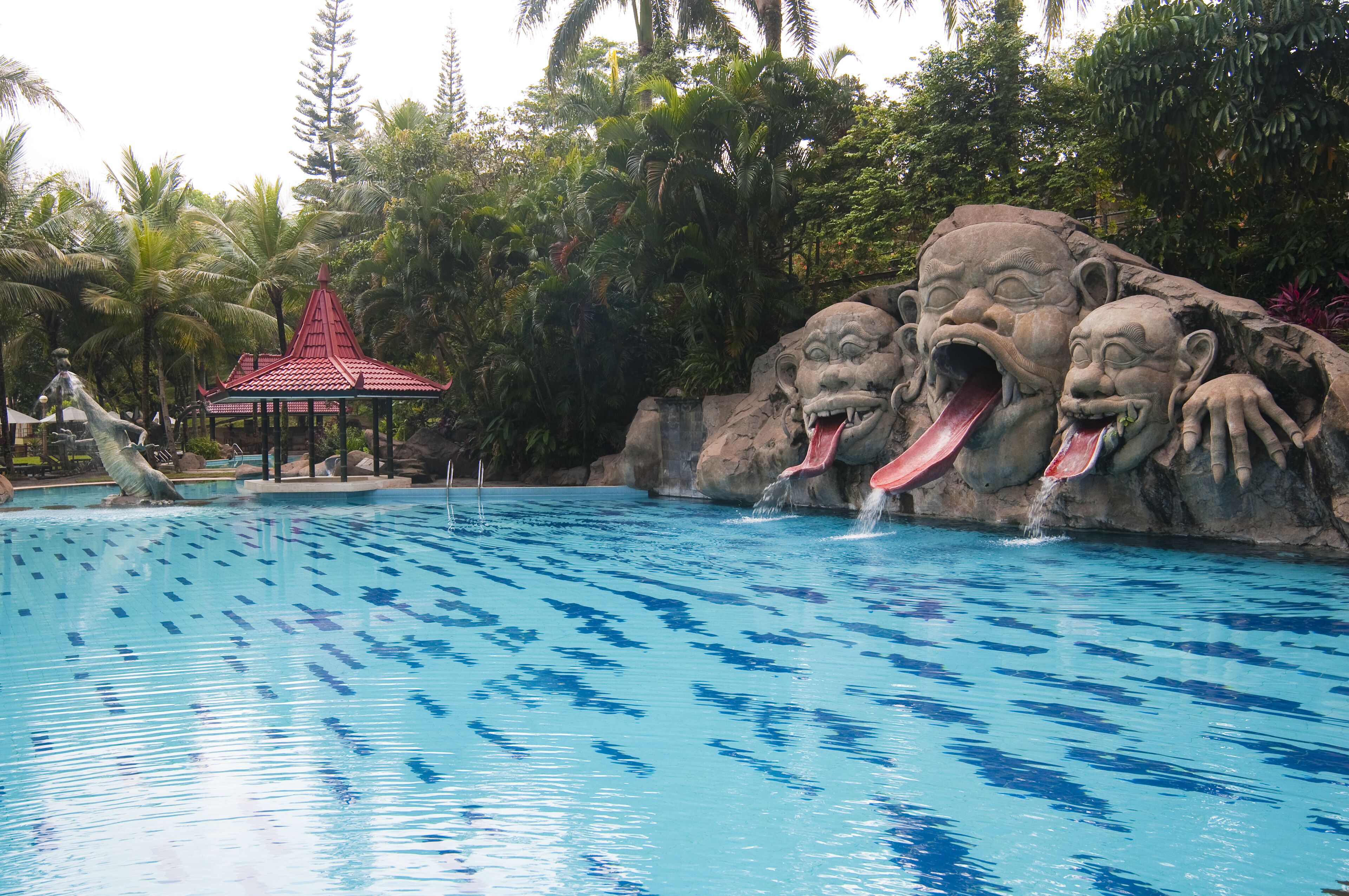 Piscina com formação rochosa e um gazebo.