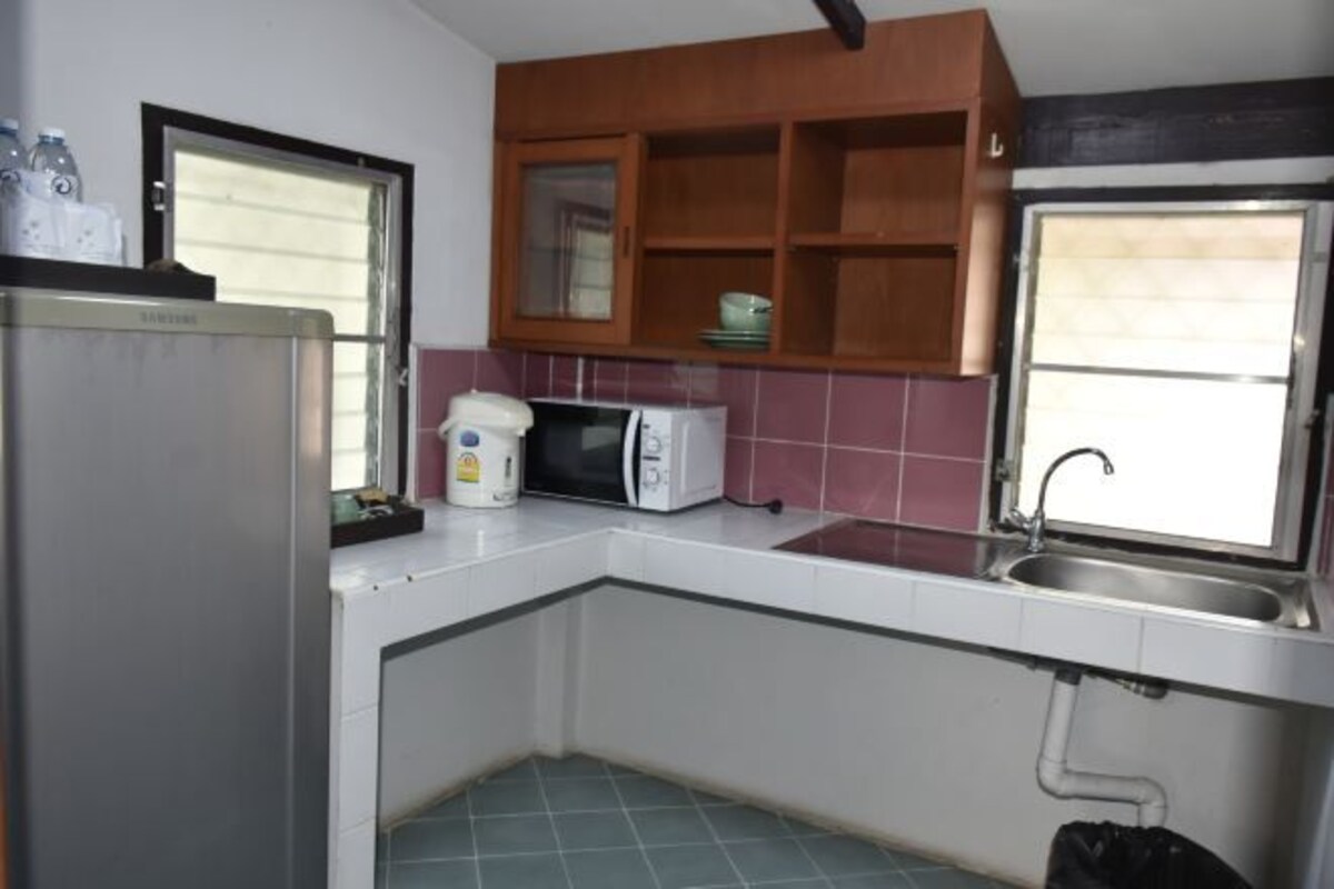 Uma cozinha compacta com geladeira, micro-ondas e pia, com uma janela acima da pia.