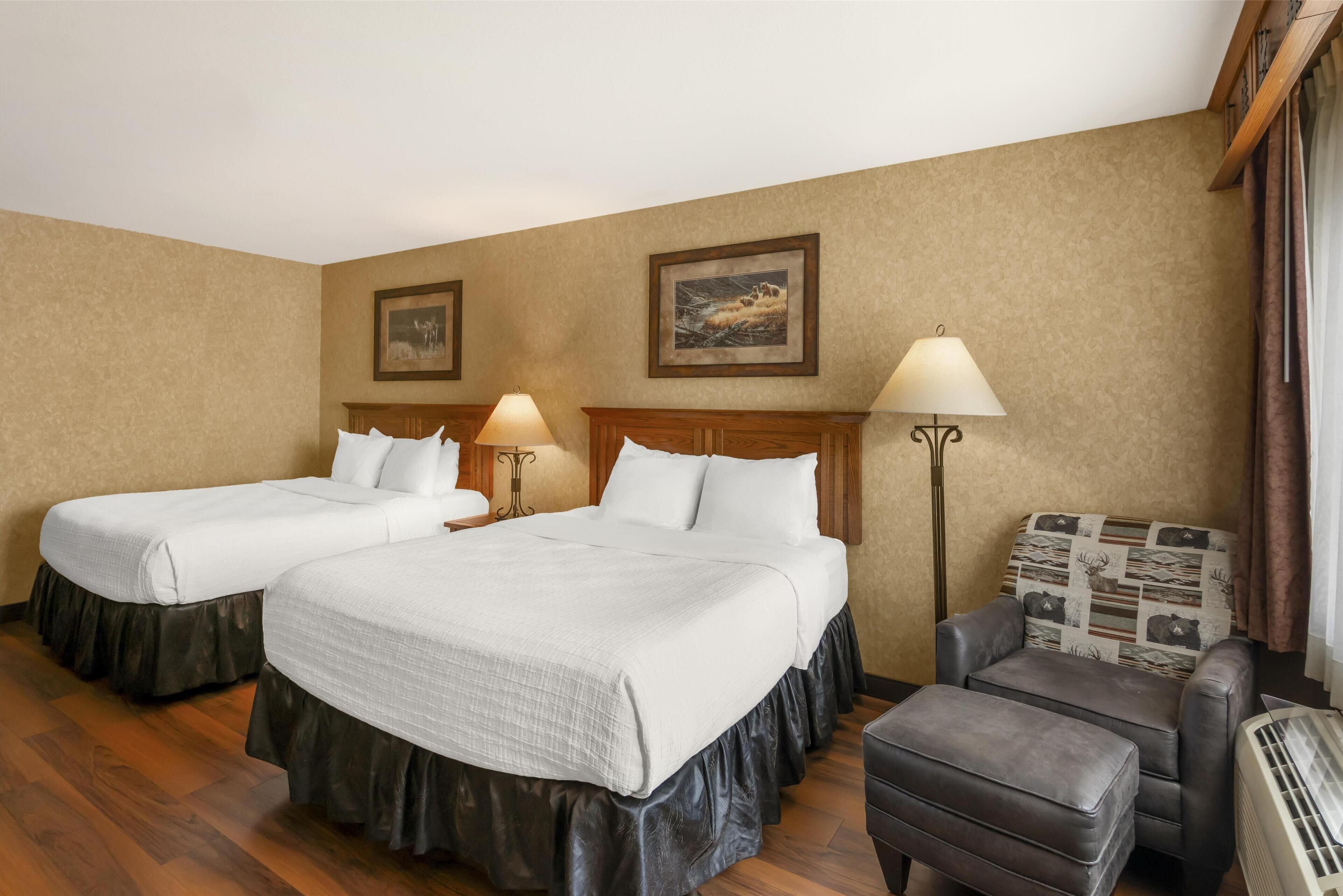 Quarto de hotel com duas camas, um sofá, uma cadeira e um aquecedor.