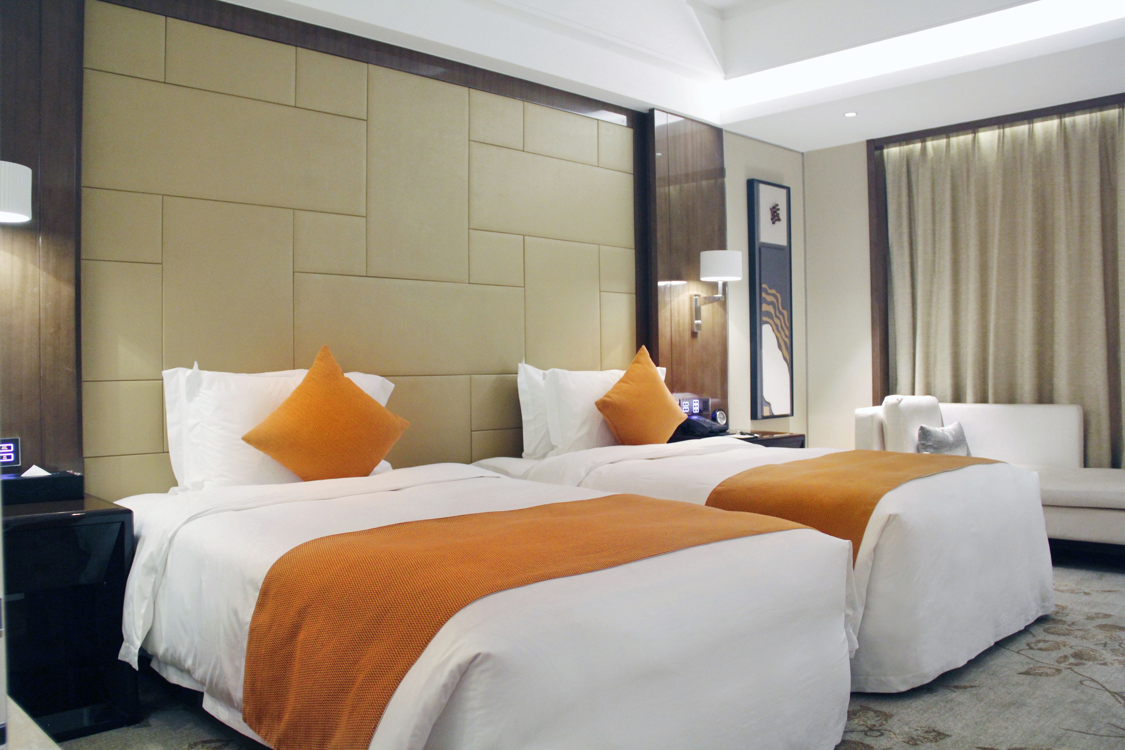 Quarto de hotel com duas camas, um sofá e um espelho grande.