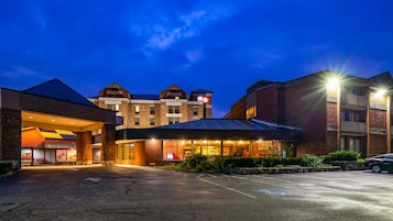 Um hotel com fachada de tijolos, vários andares e uma entrada bem iluminada.