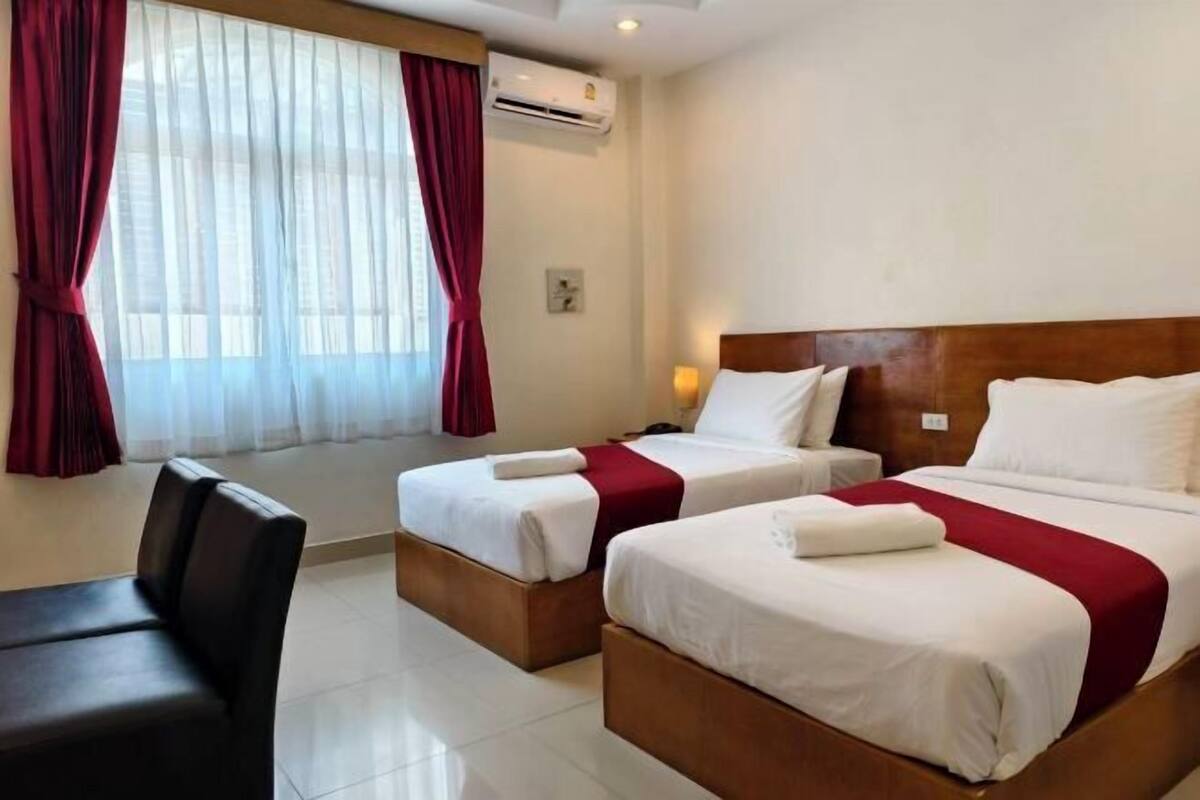 Quarto de hotel com duas camas, uma mesa e uma cadeira.