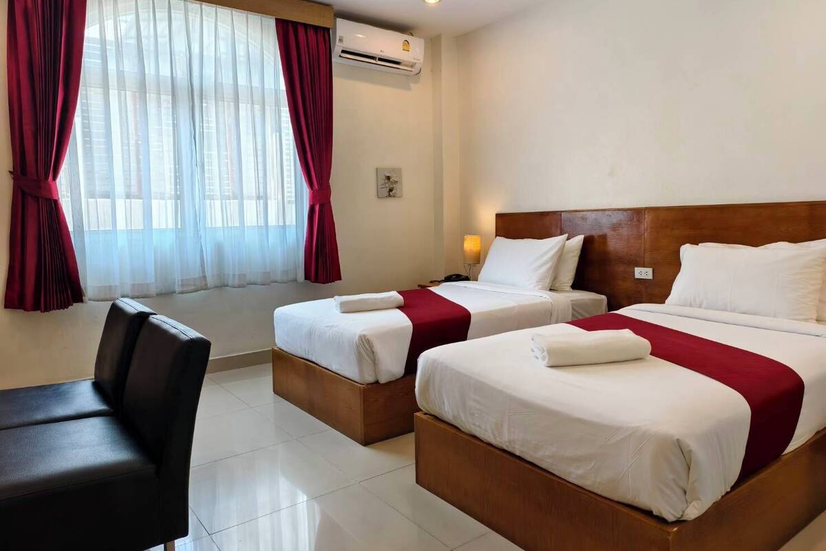 Quarto de hotel com duas camas, uma escrivaninha e uma cadeira.