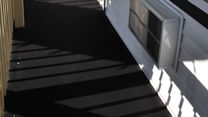 Um corredor com portas e janelas, um passeio coberto e um respiradouro na parede.