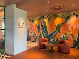 Um interior moderno com um mural na parede, duas cadeiras laranja e uma pequena mesa redonda.