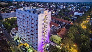 Um hotel com vários andares e um estacionamento na frente.