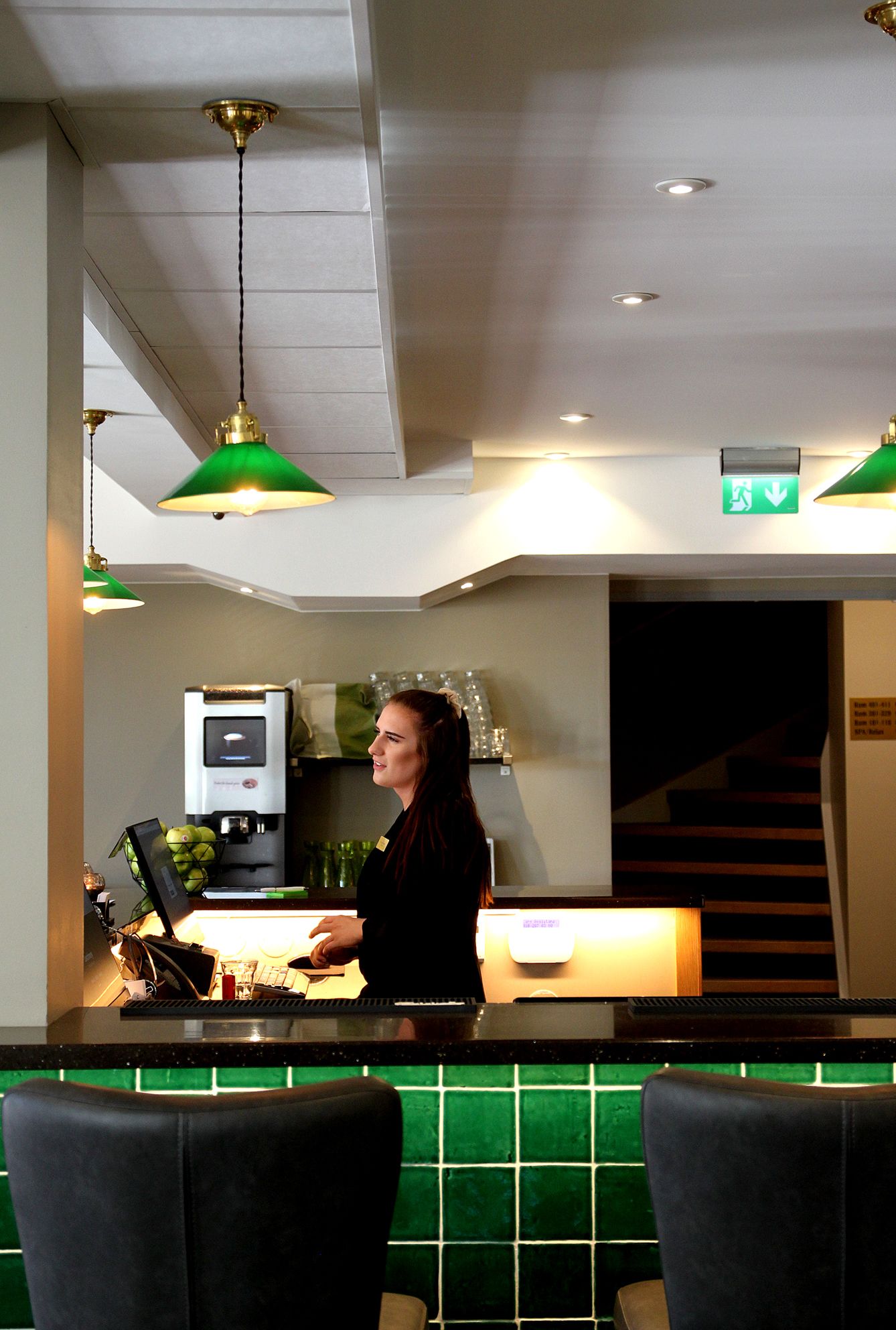 Uma área de bar com balcão, máquina de café e um espaço de estar com cadeiras.