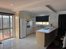 Uma cozinha moderna com uma ilha central, eletrodomésticos embutidos e uma grande janela que oferece iluminação natural.