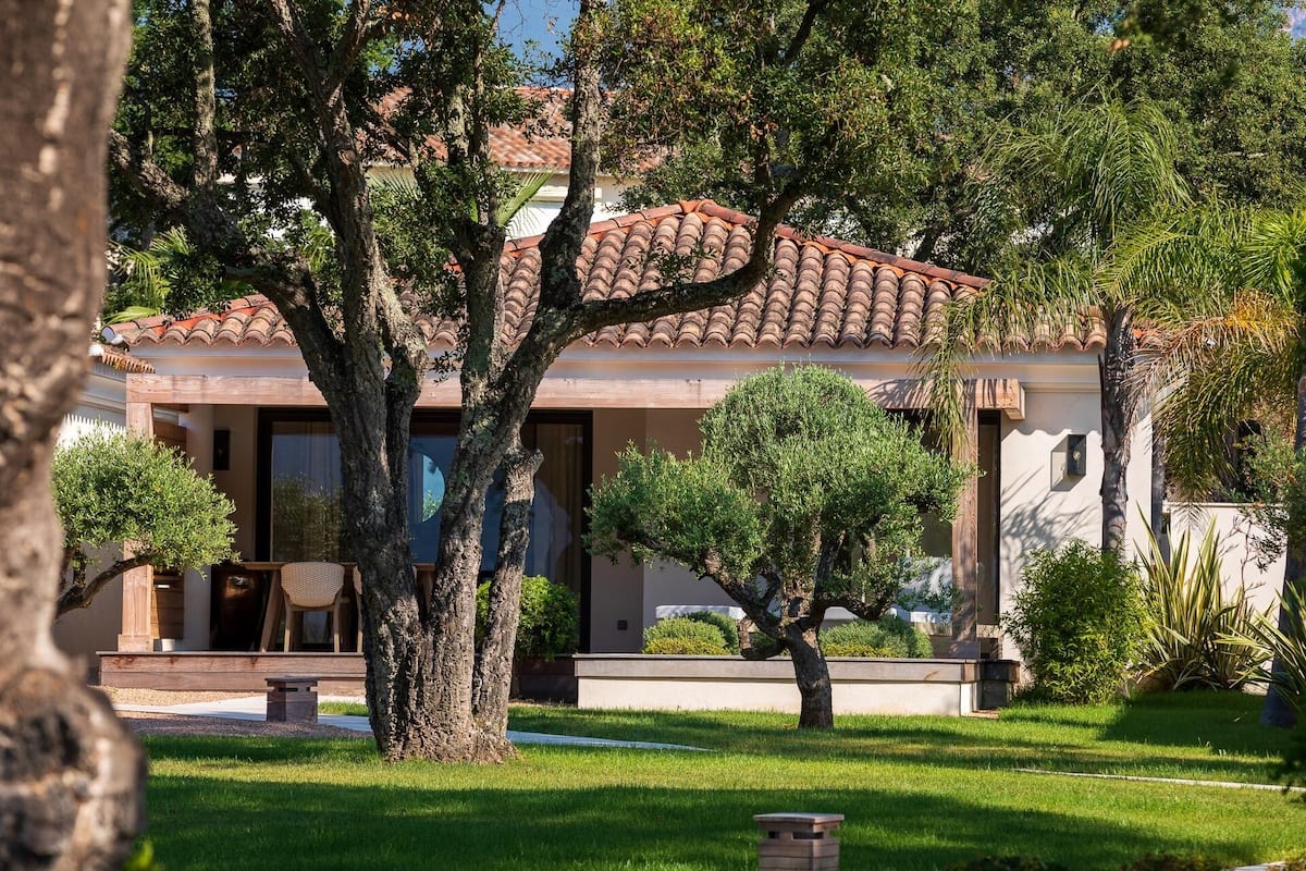 Uma vila em estilo mediterrâneo com telhado de azulejos, cercada por vegetação bem cuidada e vista desobstruída da paisagem circundante.