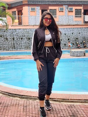 Uma pessoa parada perto de uma piscina, com um muro de pedra e um edifício ao fundo.