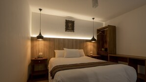 Quarto bem arrumado com uma cama grande, mesas de cabeceira, guarda-roupa e luminária suspensa.