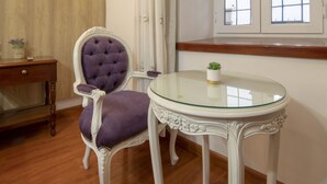 Um quarto com uma poltrona estofada roxa, uma mesa branca ornamentada e um armário de madeira.