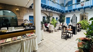 Espaçoso espaço interno com área de refeições, buffet com diversas opções de comida e varanda com grades azuis.