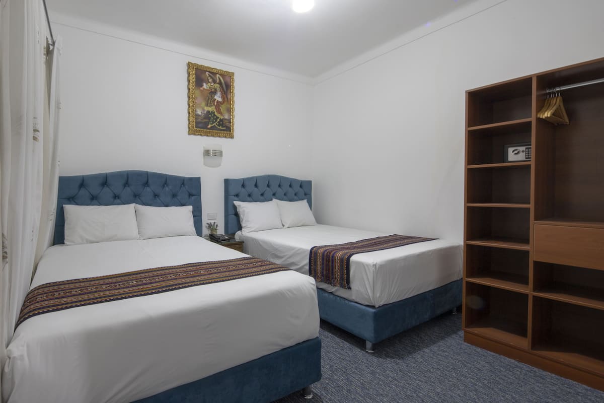 Quarto de hotel com duas camas, um guarda-roupa e um quadro na parede.