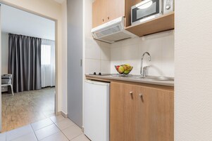 Cozinha compacta com micro-ondas, pia e uma cesta de frutas na bancada.