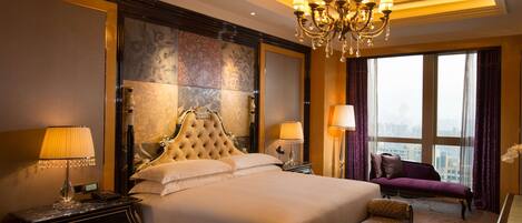 Quarto de hotel luxuoso com uma cama grande, um chaise longue, um lustre e vista para a cidade.