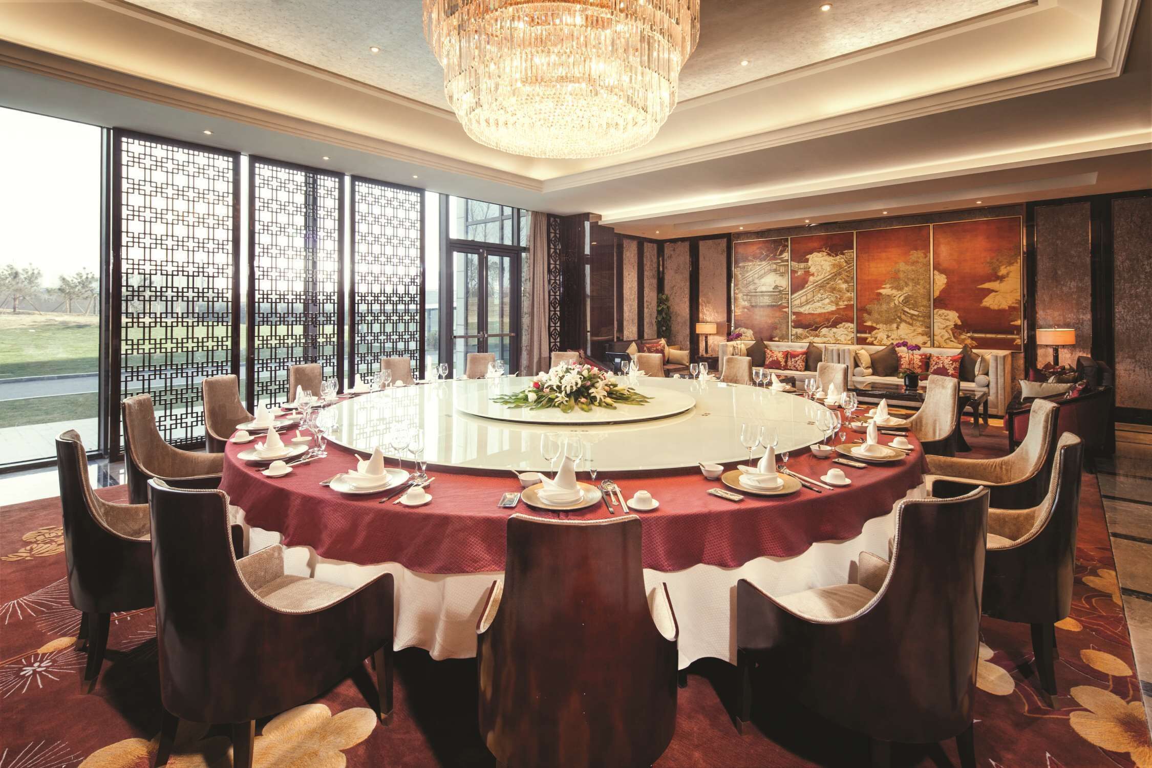 Uma sala de jantar espaçosa com uma mesa redonda posta para refeição, cercada por cadeiras confortáveis.