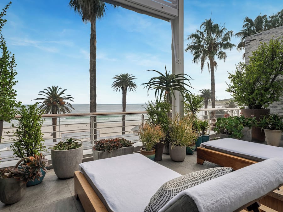 Uma varanda com vista para a praia, plantas em vasos e um espaço de estar com vista.