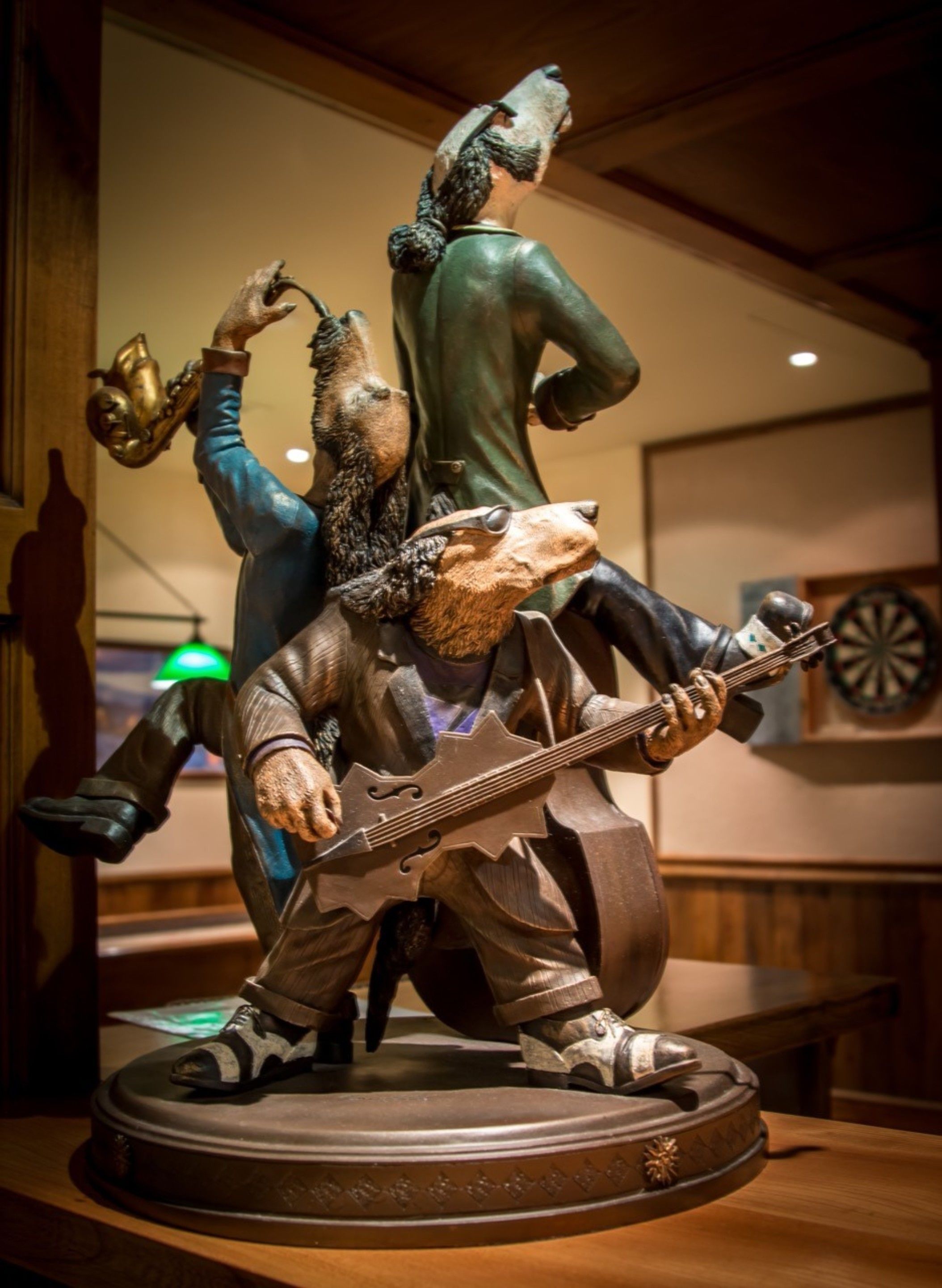 Uma estátua de um urso tocando guitarra, um urso segurando um troféu e um urso usando chapéu coco.