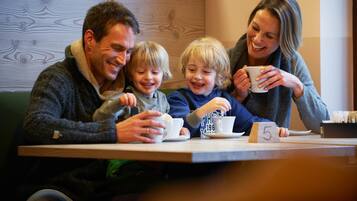 Uma família de quatro pessoas sentada à mesa, com jogos de lugar numerados, indicando um ambiente organizado como um restaurante ou café.