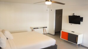 Quarto com cama, mesa de cabeceira, cômoda, televisão e ventilador de teto.